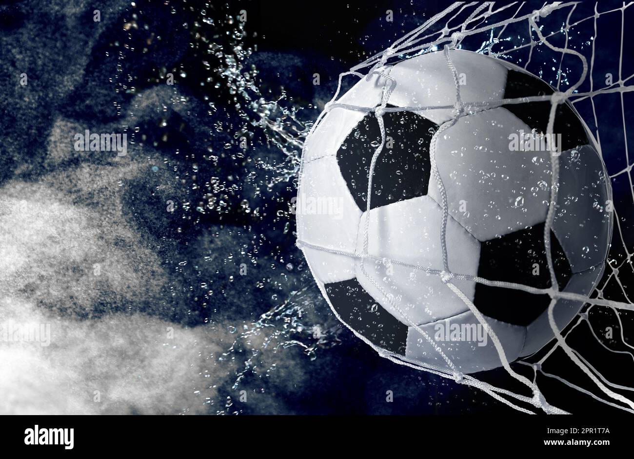 Soccer ball in net with splash water and white smoke against dark ...