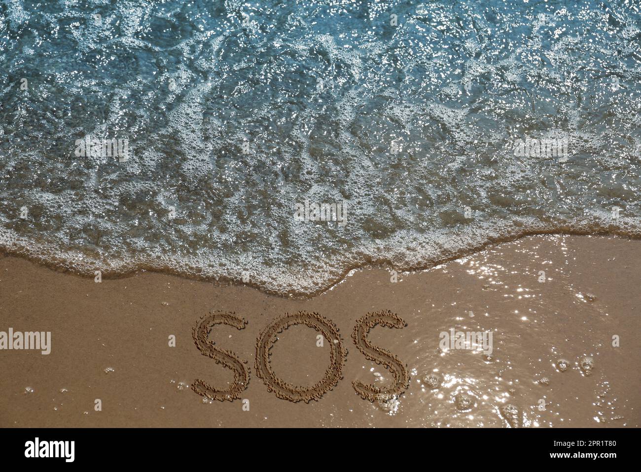 SOS message drawn on sandy beach near sea, above view Stock Photo - Alamy
