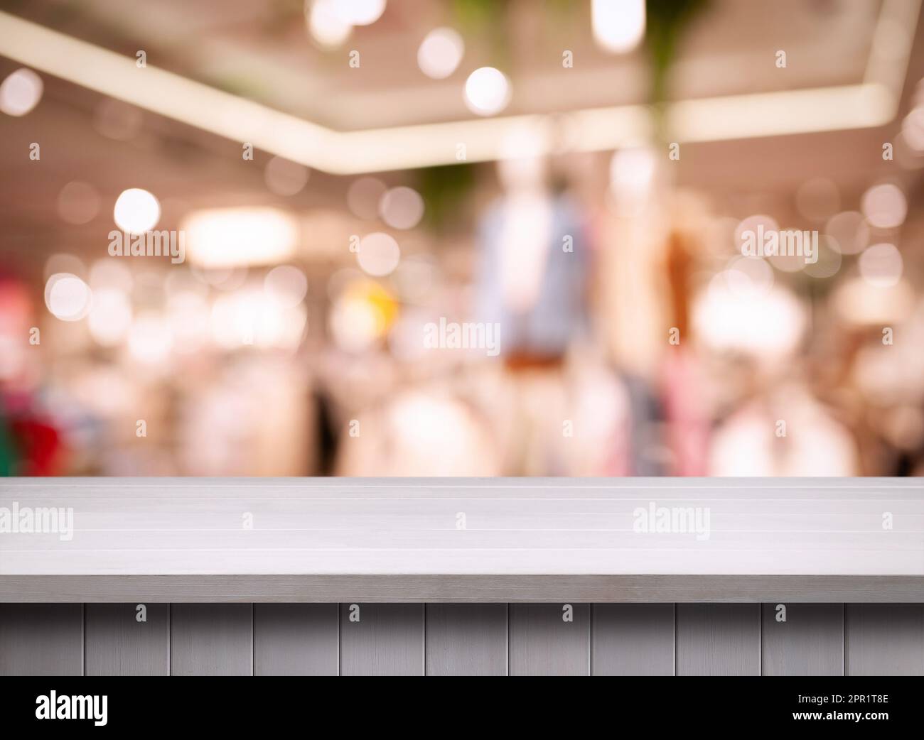 Empty white wooden surface and blurred view of clothes store interior ...