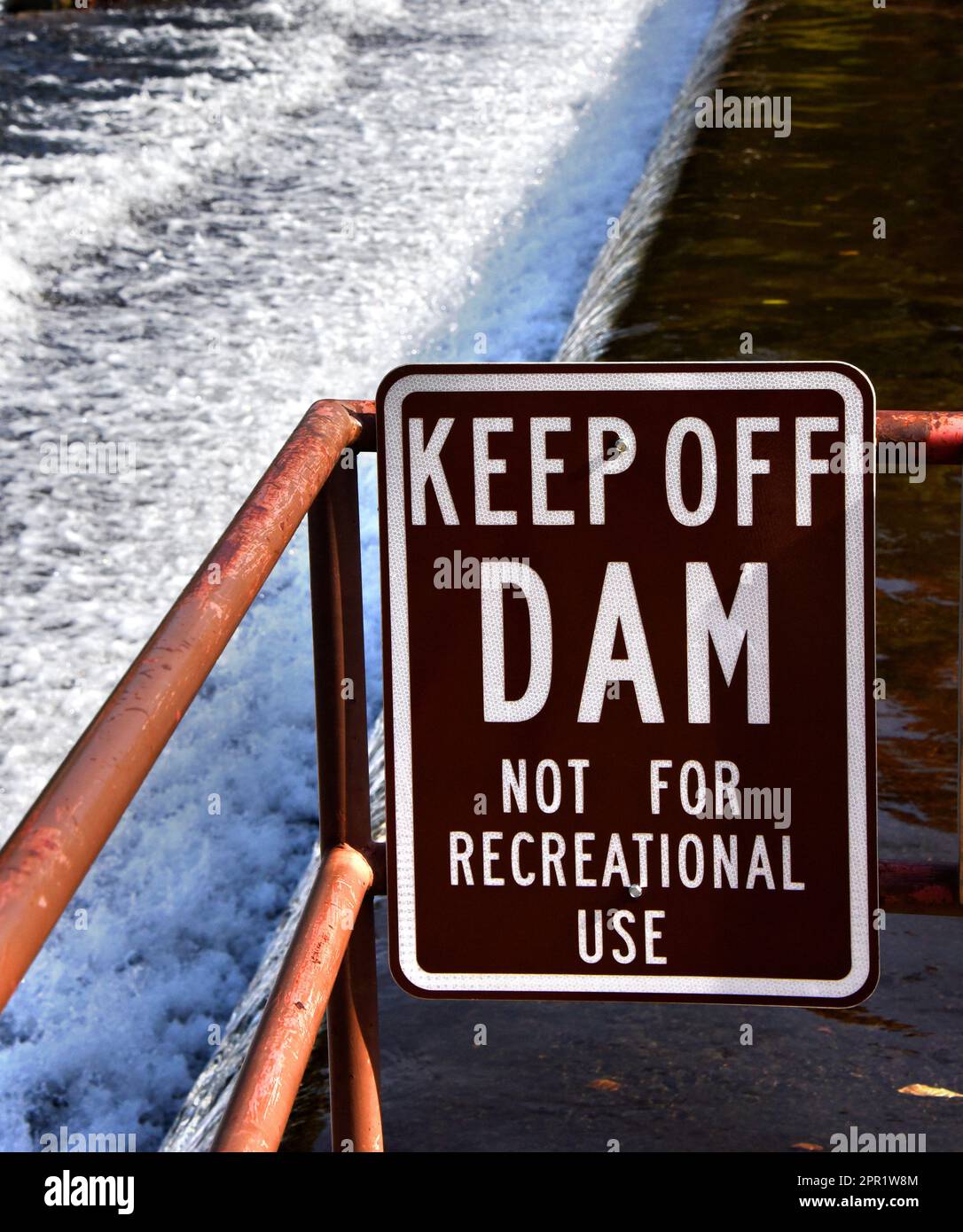 Brown sign, with white lettering, warns visitors to keep off dam ...