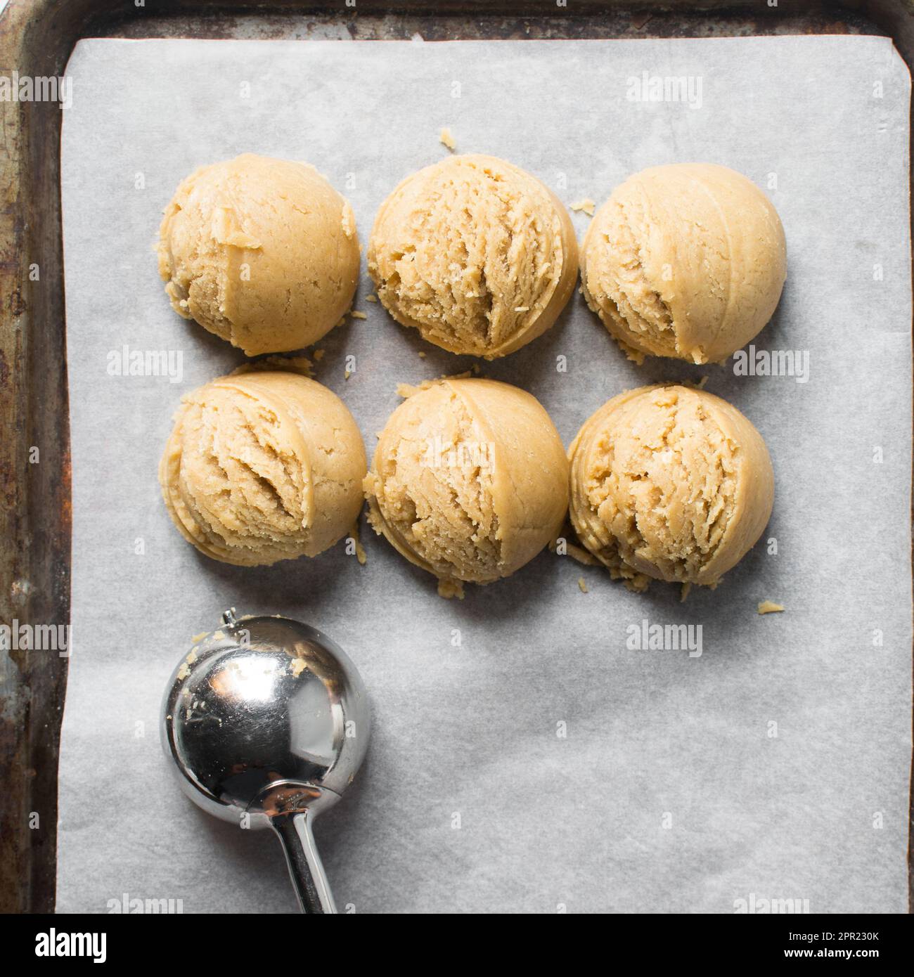 Scoops of vanilla cookie dough on a parchment lined cookie sheet, plain ...