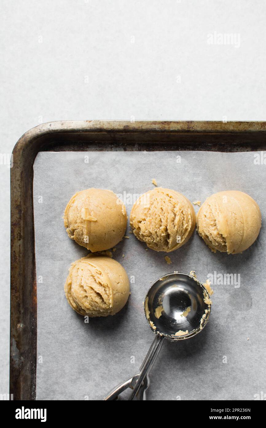Scoops of vanilla cookie dough on a parchment lined cookie sheet, plain ...