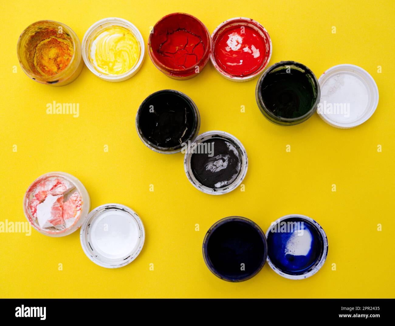 Colored lids on yellow. Top view Stock Photo - Alamy