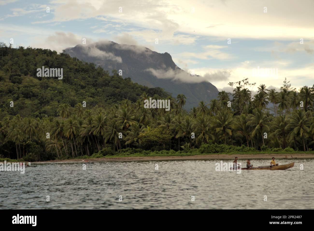 People are traveling by canoe on coastal water, photographed in a ...