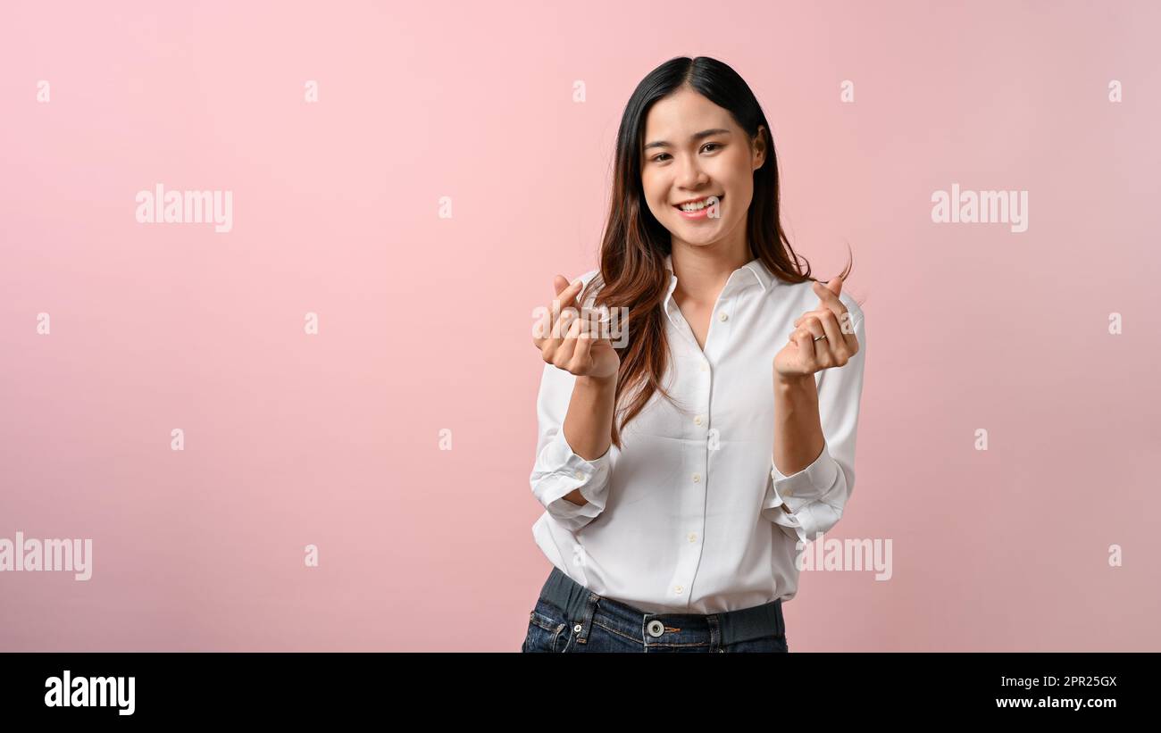 Young Asian woman showing mini heart sign isolated on pink background ...