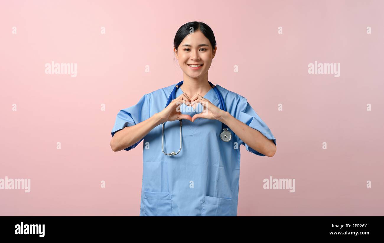 Young happy beautiful Asian doctor showing a heart symbol hand sign ...