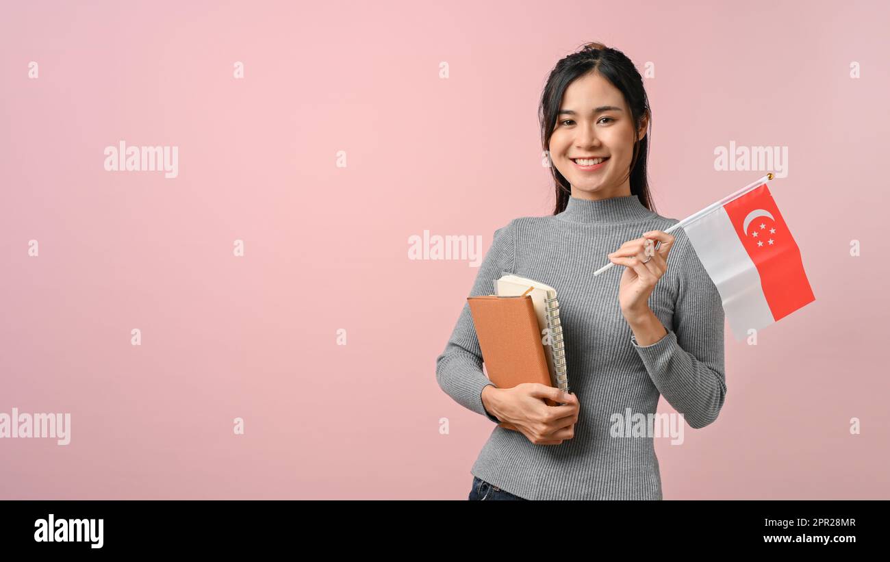 Beautiful Asian student showing Singapore flag on pink isolated ...
