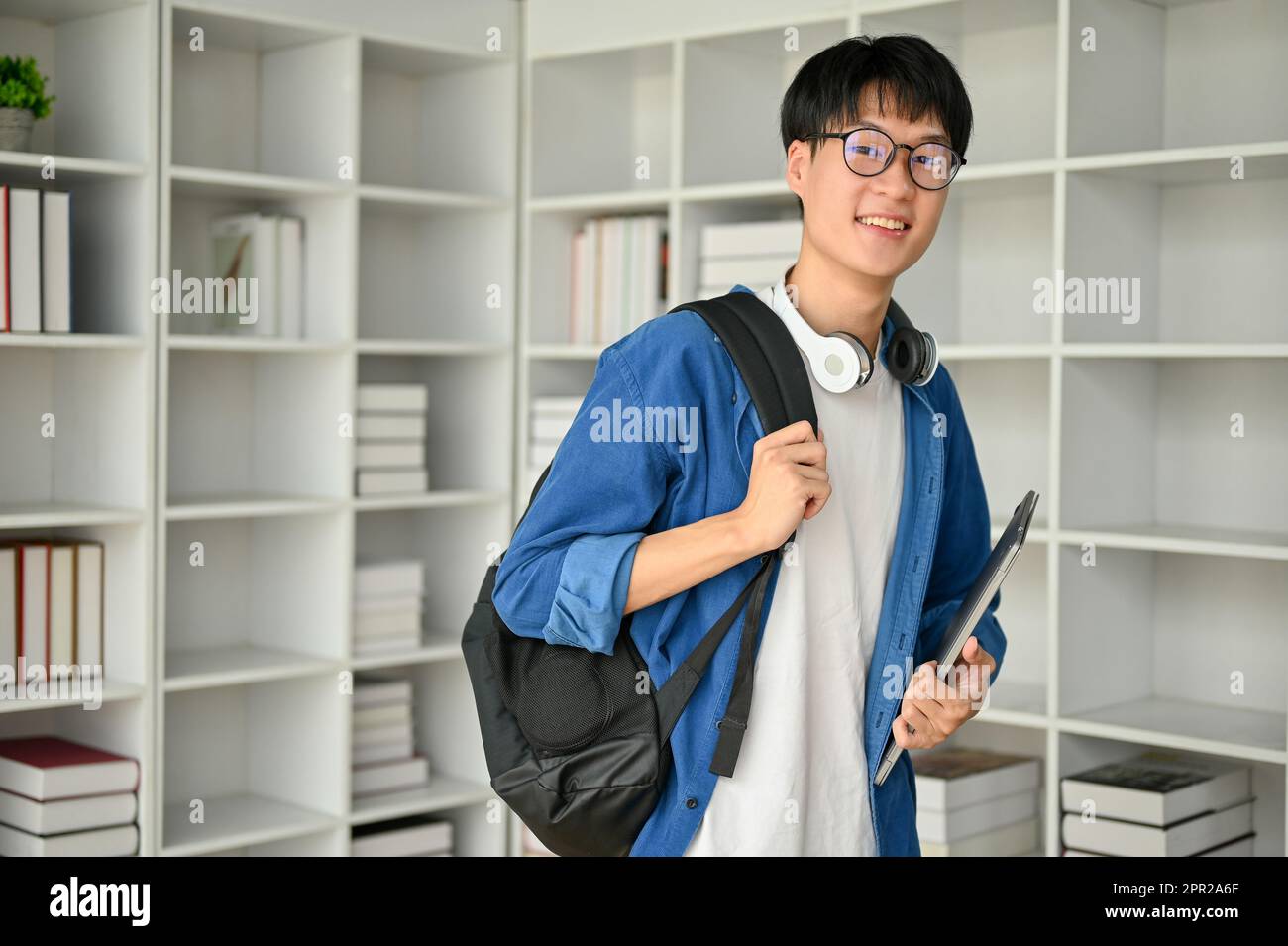 Portrait of young college student smiling at the camera while carrying ...