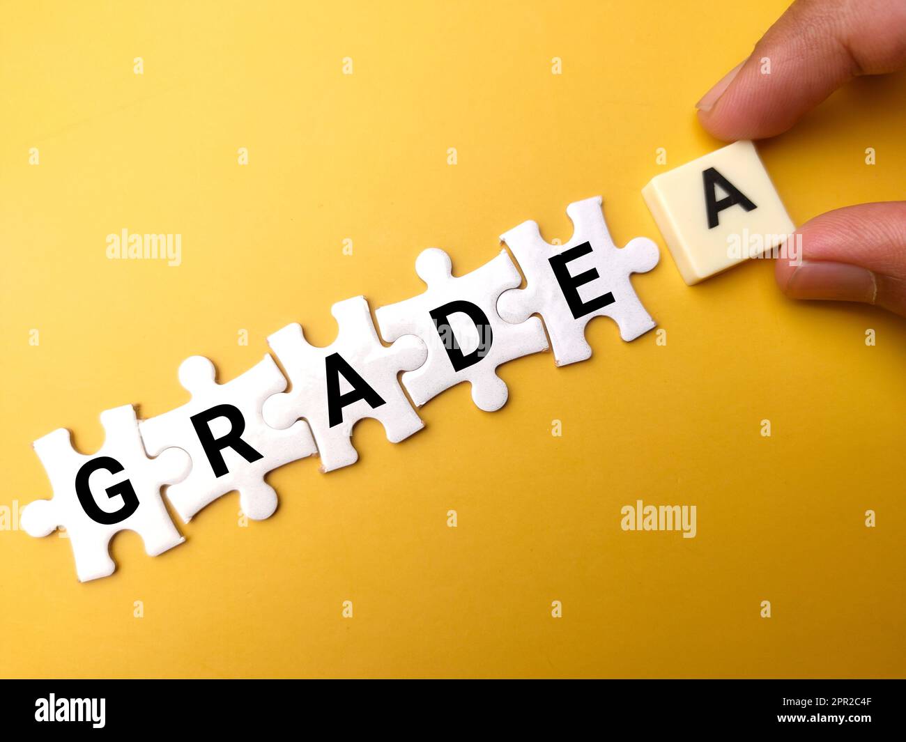 Hand holding toys word with white puzzle with the word GRADE A Stock ...