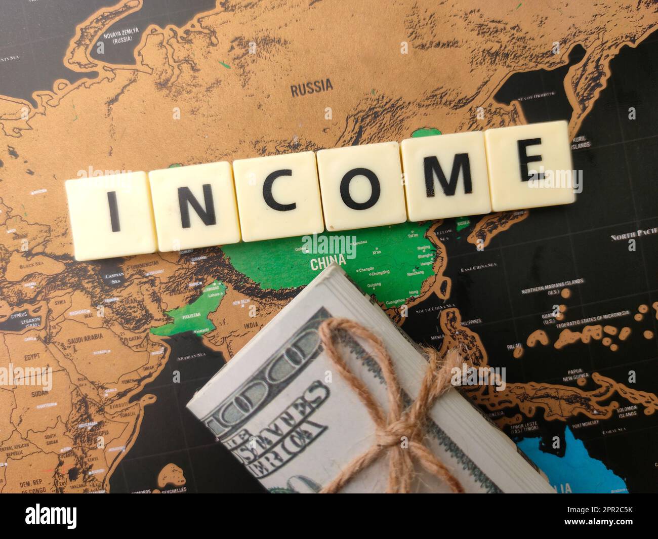 Toys word and banknotes with the word INCOME on a world map background ...