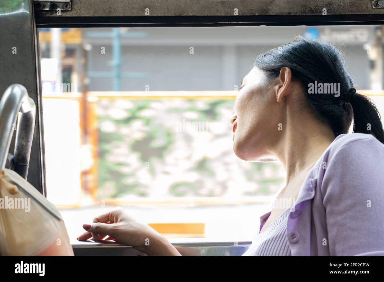 A young woman looks out of the window of a moving bus Stock Photo - Alamy