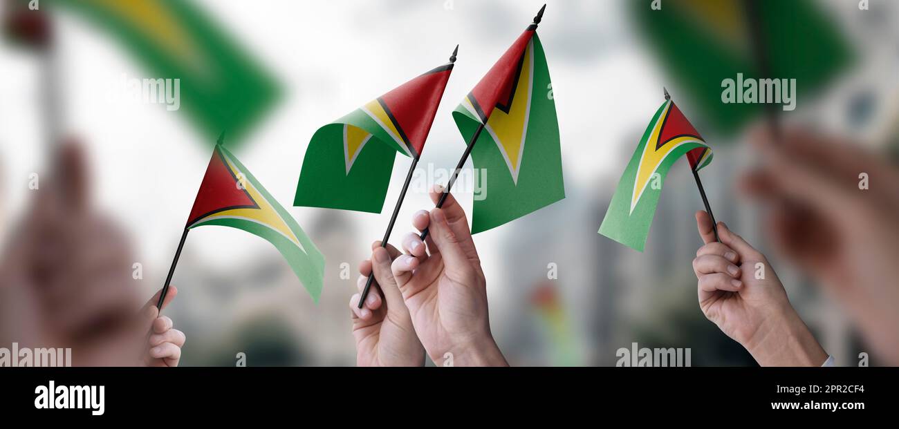 A group of people holding small flags of the Guyana in their hands ...