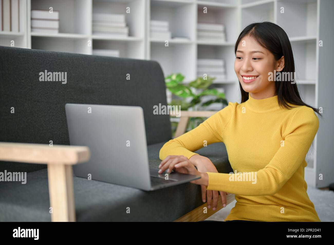 Young happy Asian woman using laptop computer while sitting on the ...