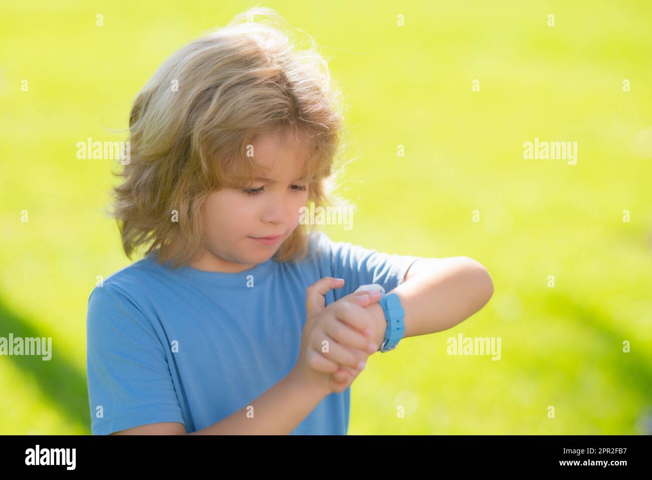 Child checking smart watch, looks on the time and hurrying. Portrait of ...