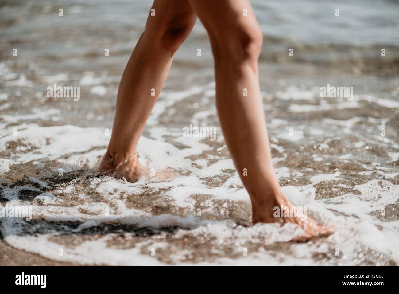 A woman walks along the beach, legs close-up. Barefoot woman sta Stock ...