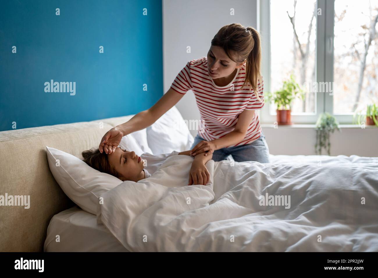 Caring mother checking temperature of sick daughter, taking care of ...