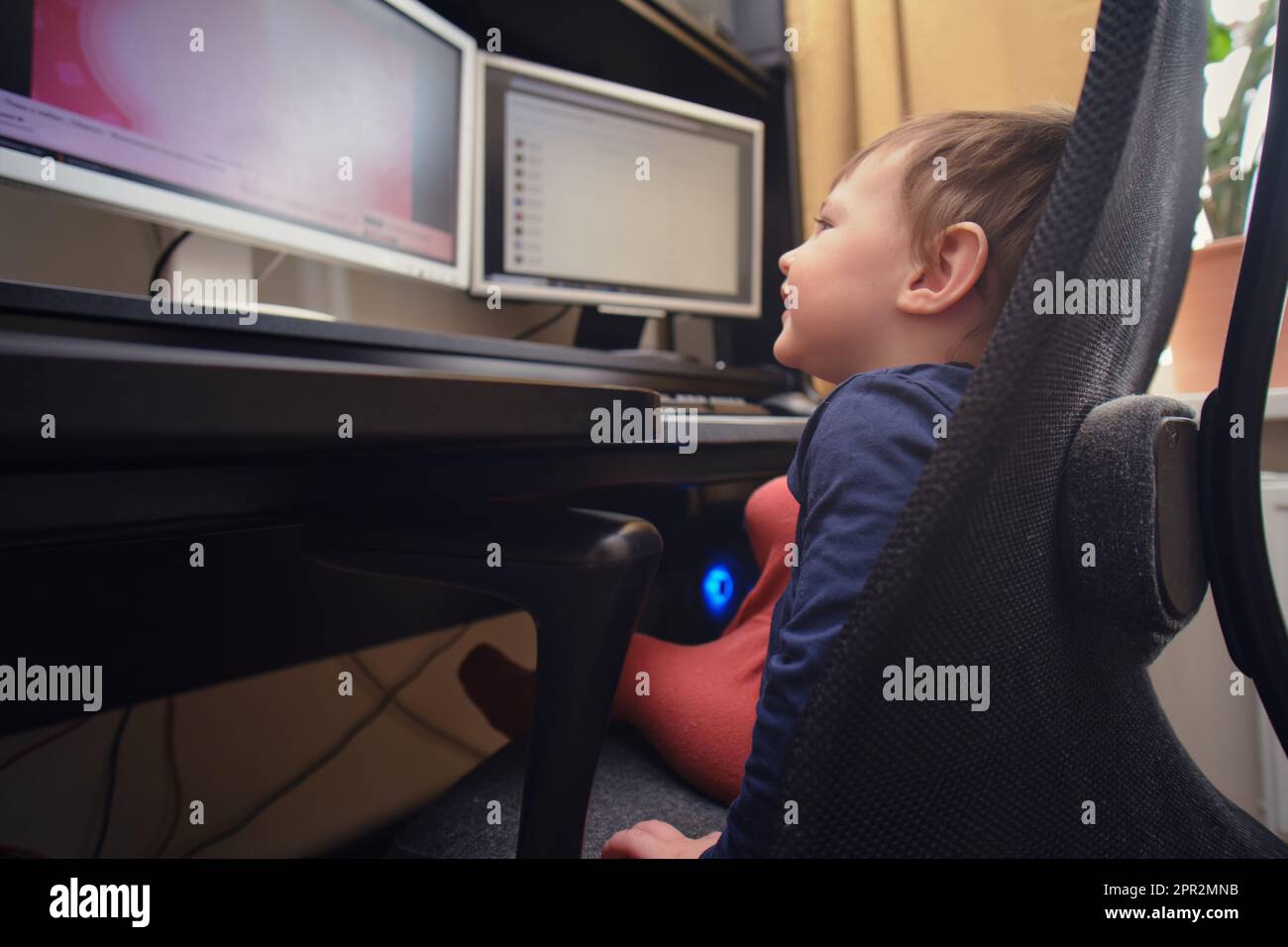 Toddler baby works on a computer with a keyboard and mouse. Happy child ...