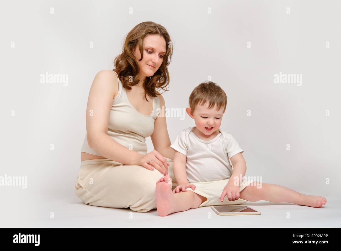 Happy baby with mother looking into digital tablet on studio white ...