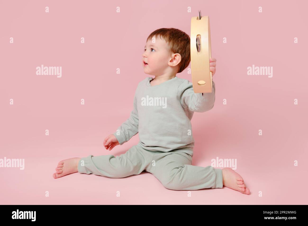 Happy toddler baby with a musical instrument tambourine on a studio ...