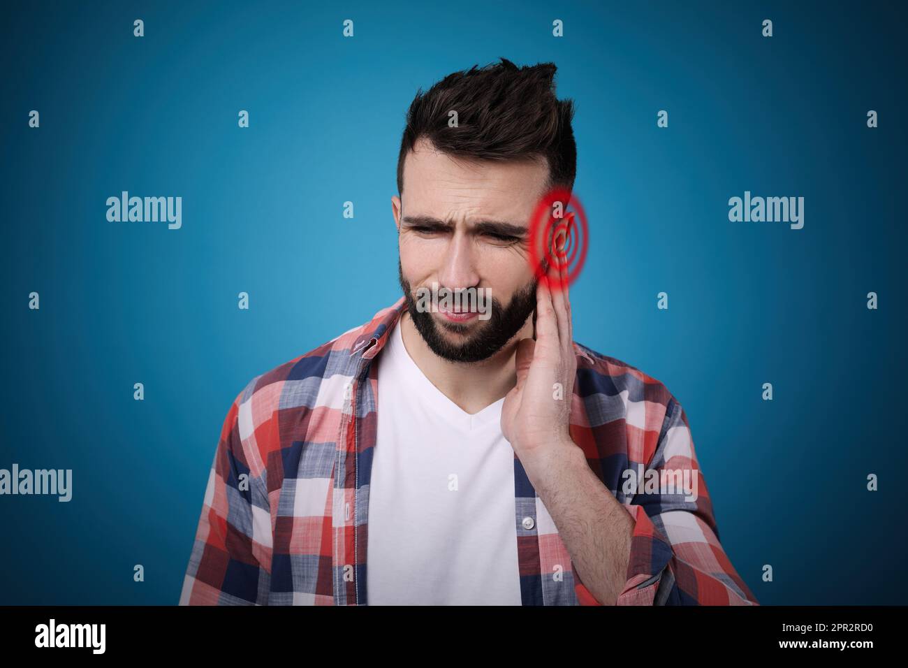 Man suffering from ear pain on blue background Stock Photo - Alamy