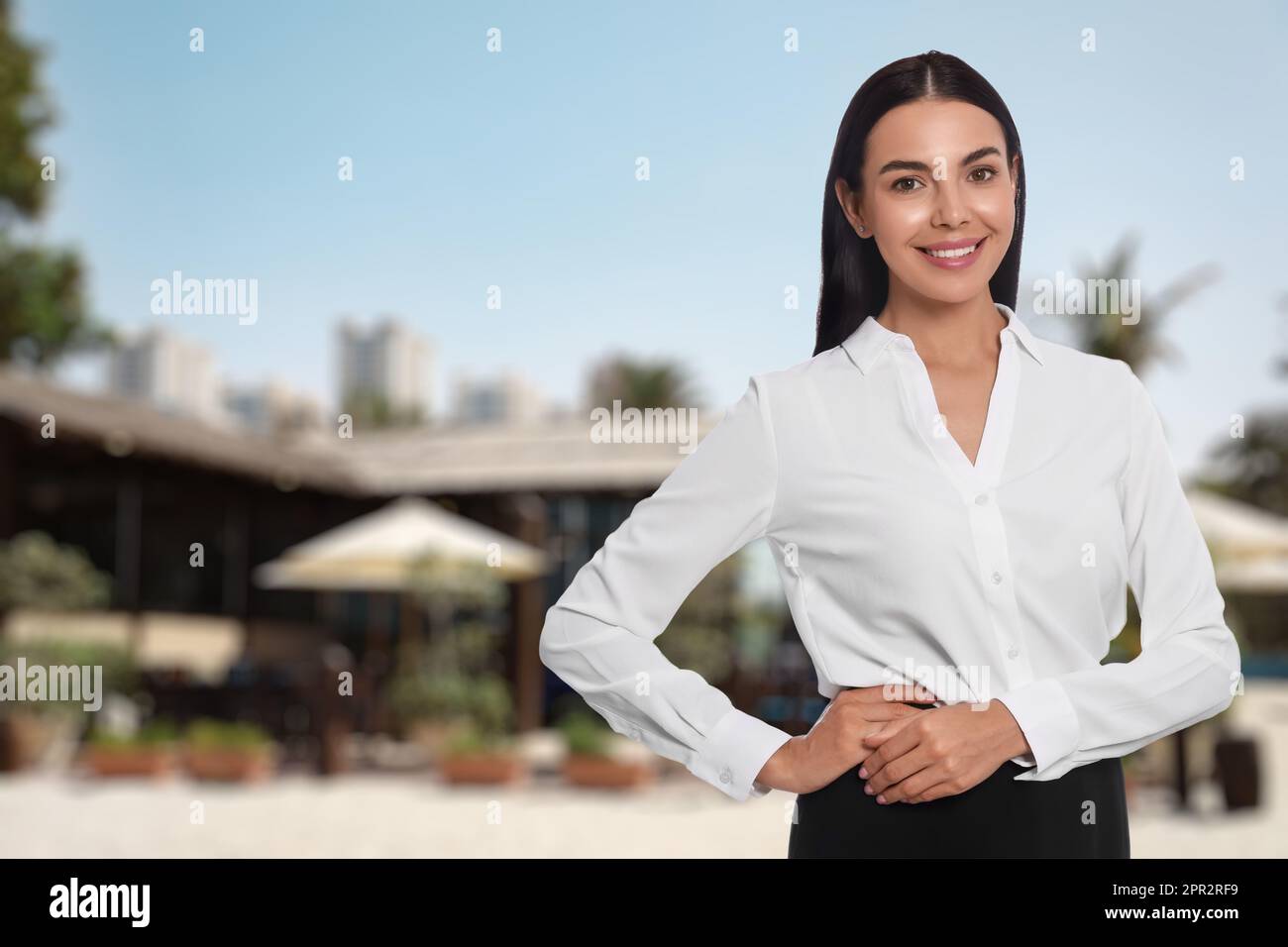 Portrait of hostess in uniform and blurred view of restaurant on sunny ...
