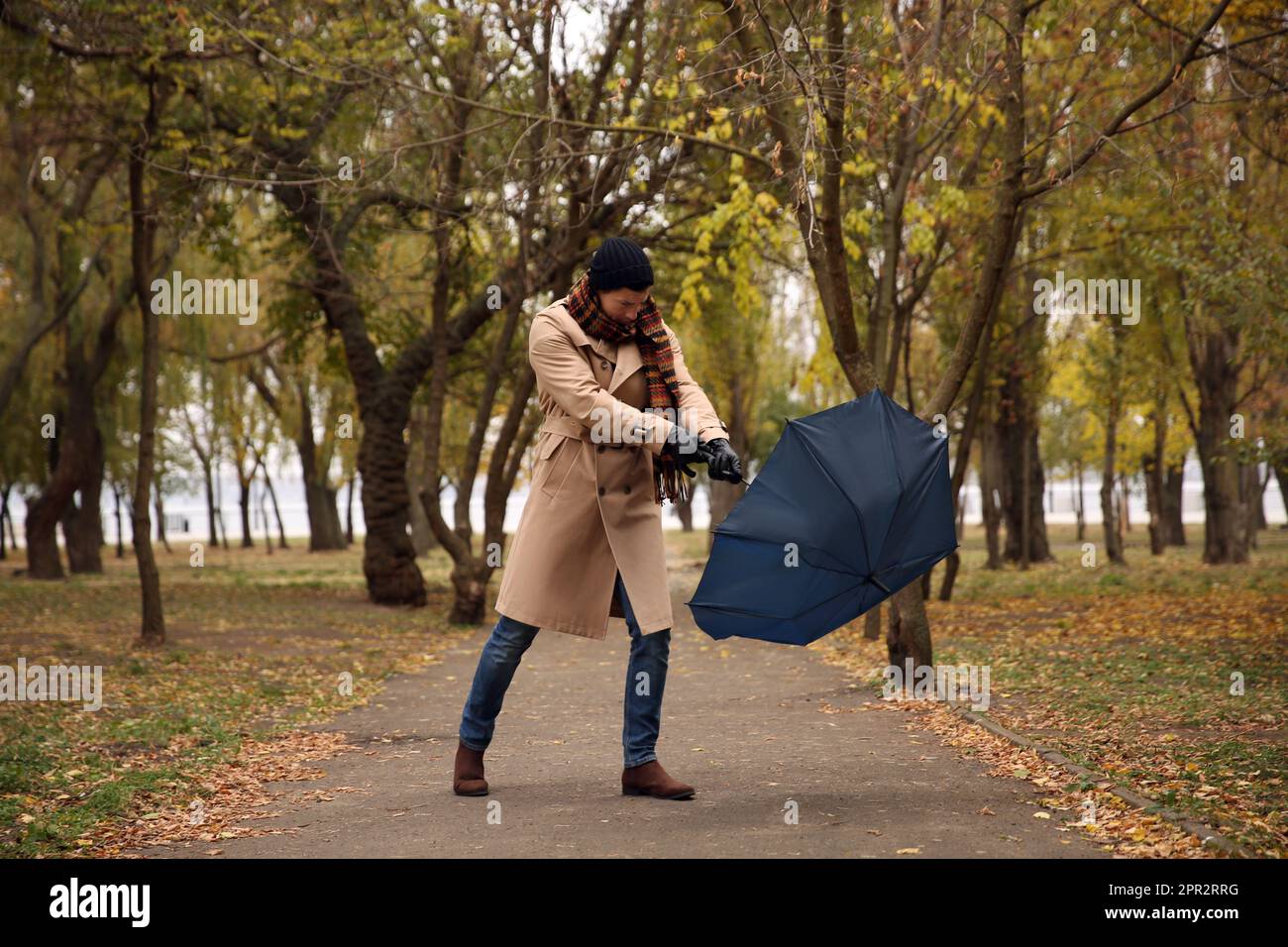 Man with blue umbrella caught in gust of wind outdoors Stock Photo - Alamy