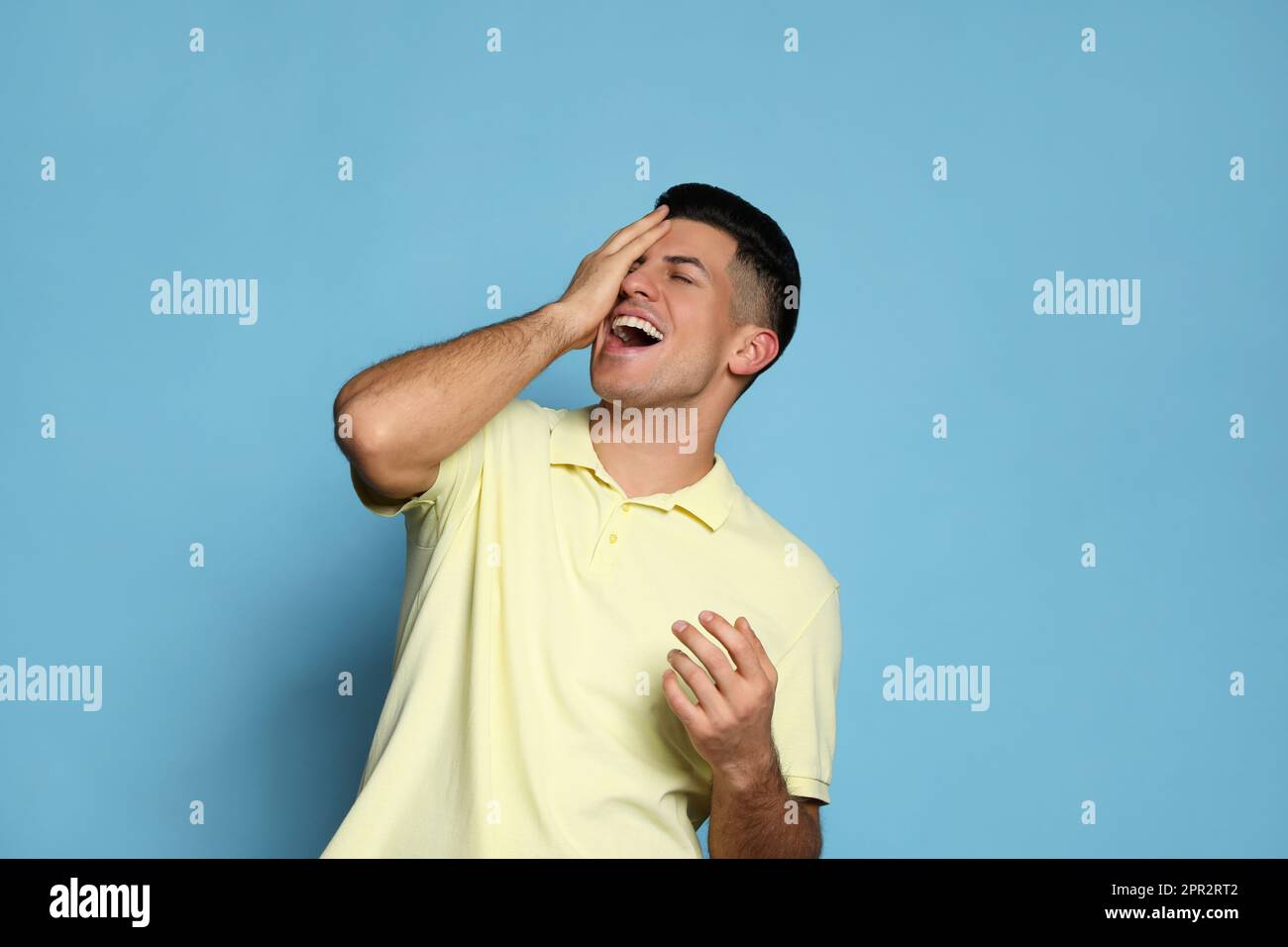 Handsome man laughing on light blue background. Funny joke Stock Photo ...