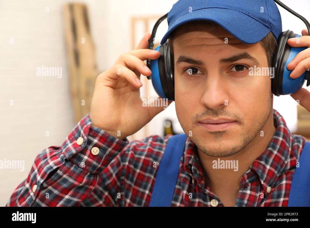 Worker wearing safety headphones indoors. Hearing protection device ...