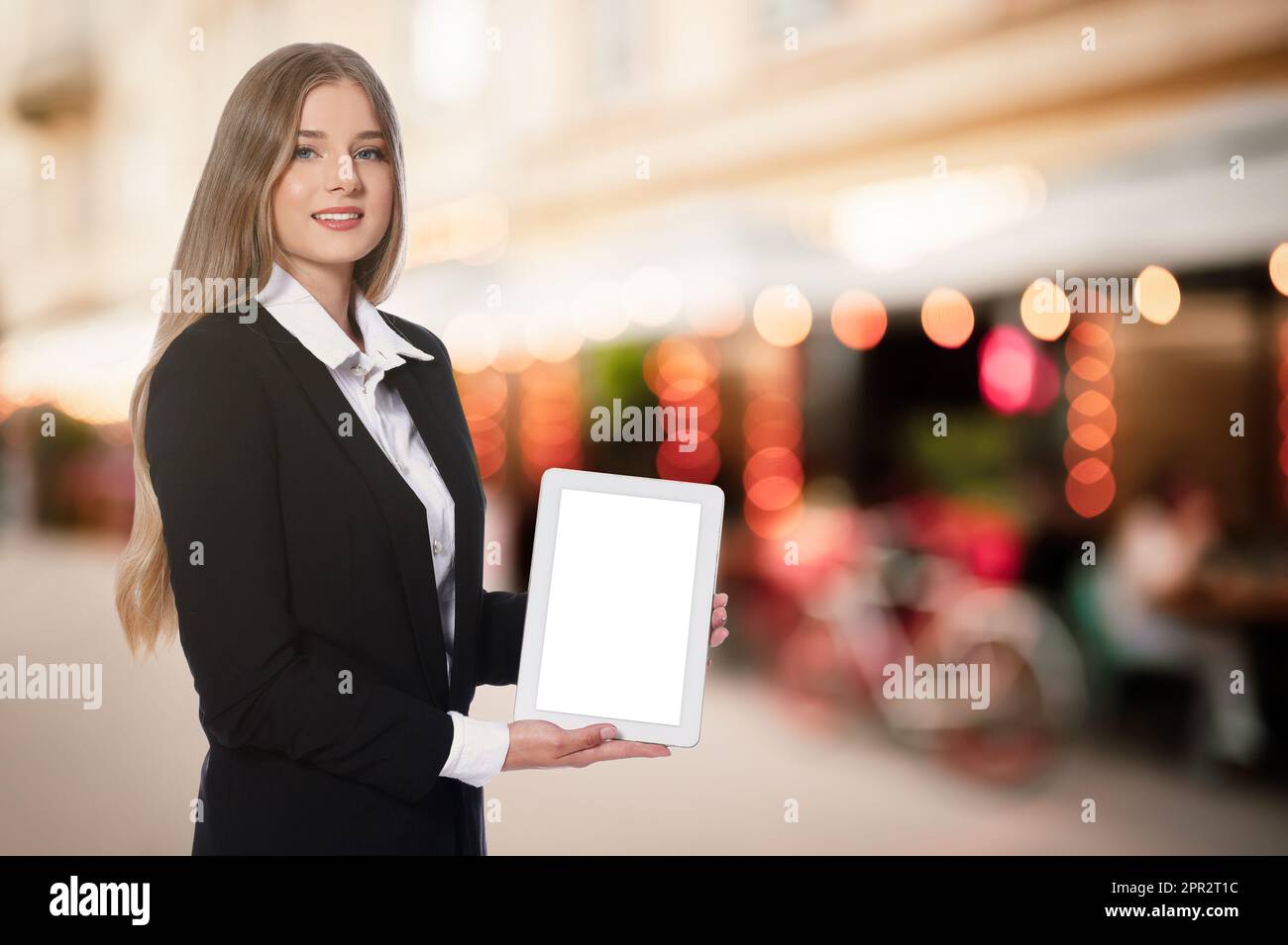 Portrait of hostess in uniform with tablet and blurred view of cafe ...