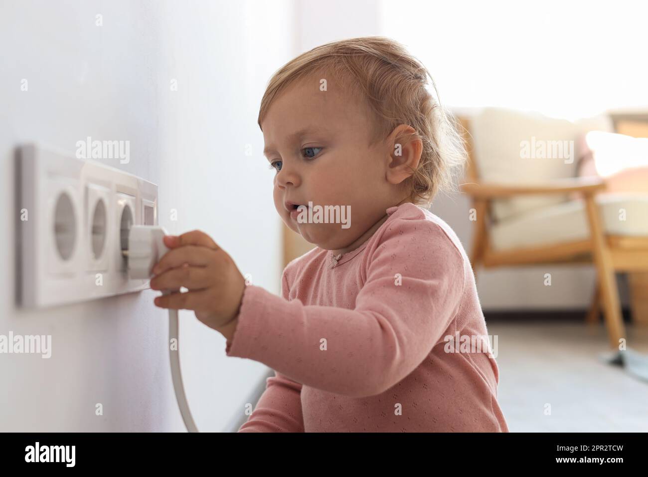 Cute baby playing with electrical socket and plug at home. Dangerous ...