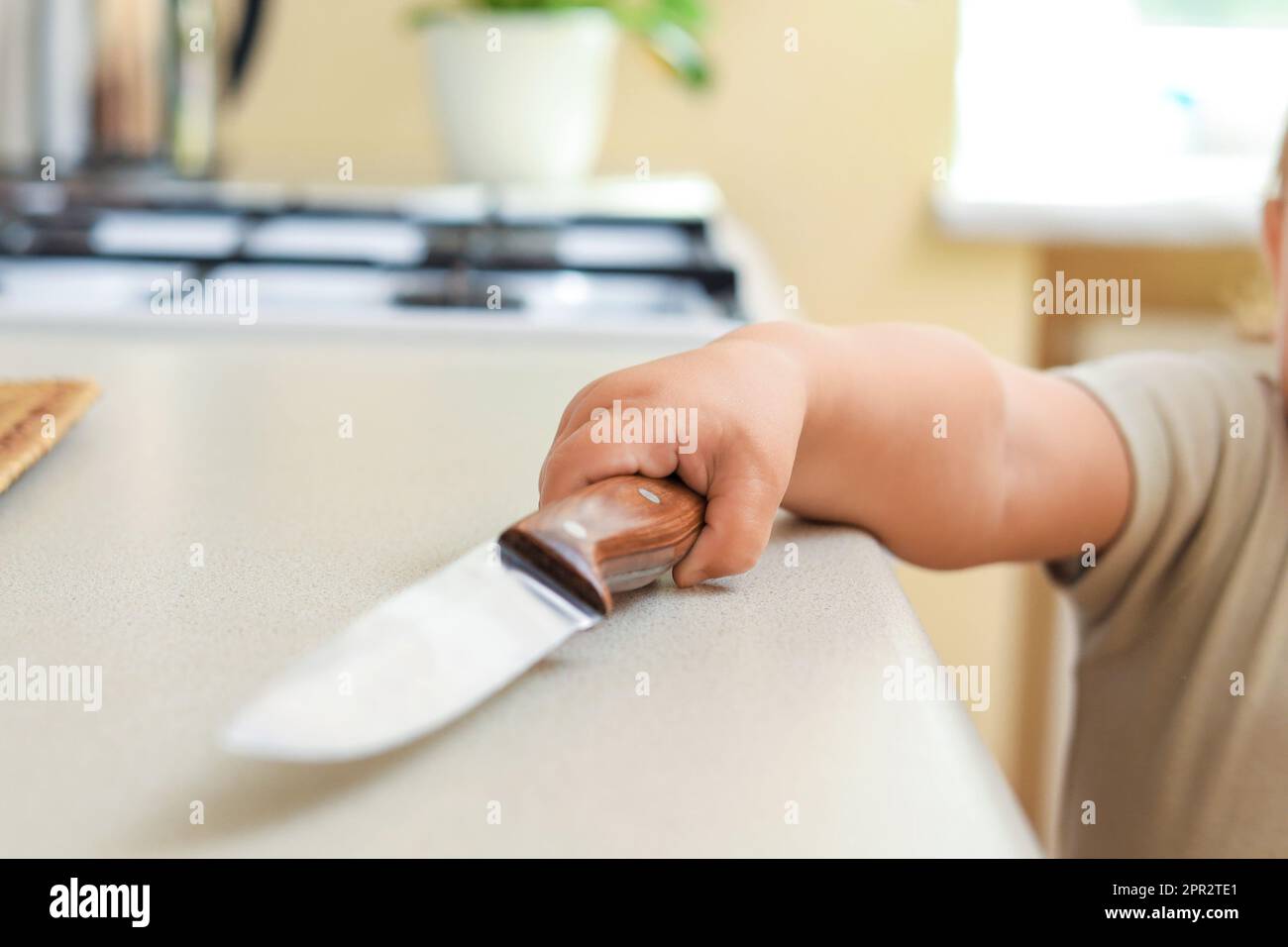 Child holding sharp knife, closeup. Dangers in kitchen Stock Photo - Alamy