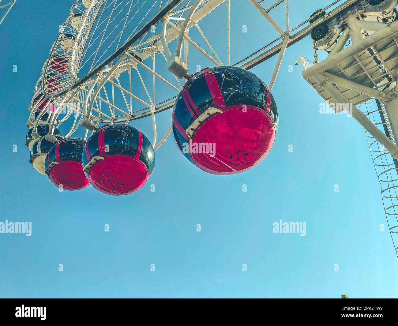 Ferris wheel in the city center against the blue sky. red booths rise ...