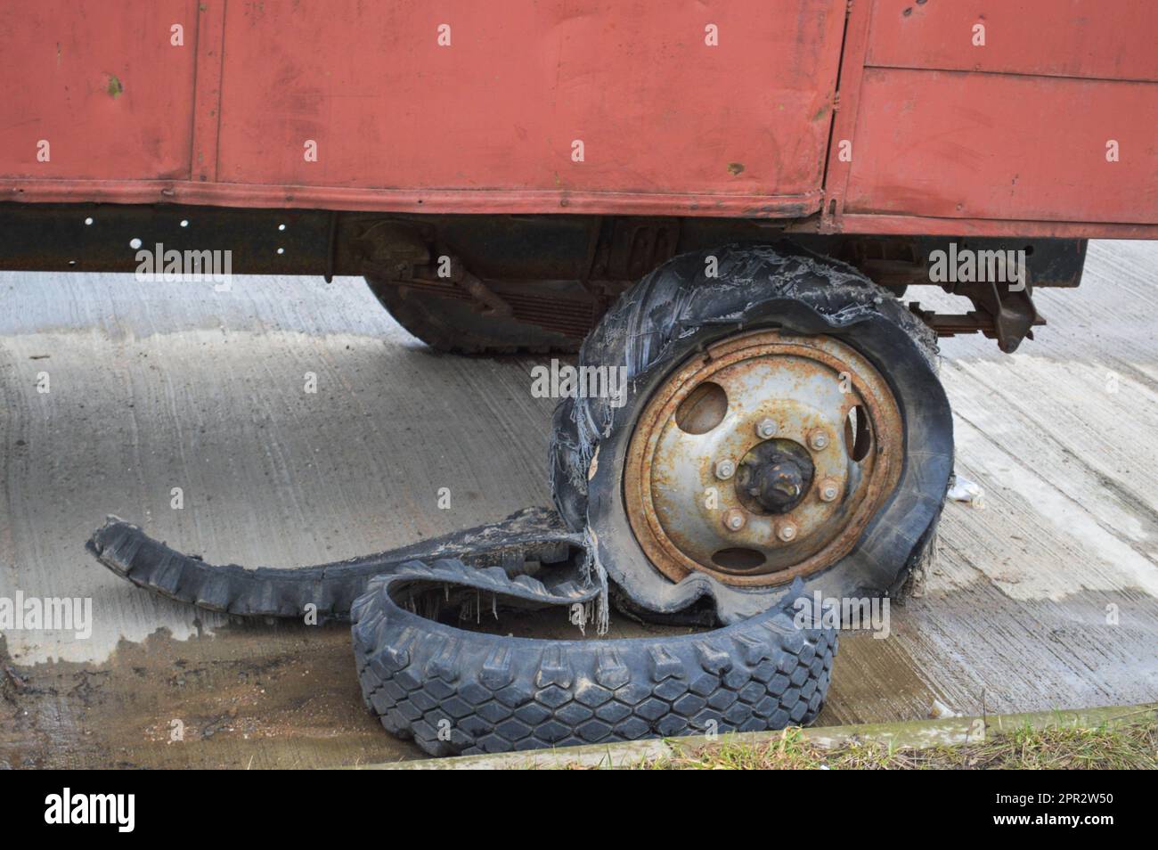 A large black rusty rubber wheel with a torn worn out broken bad old ...