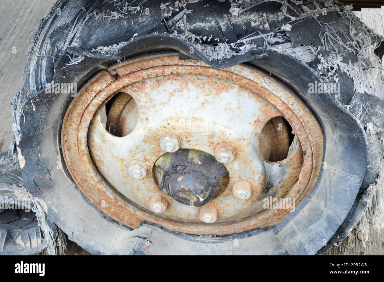 A large black rusty rubber wheel with a torn worn out broken bad old ...