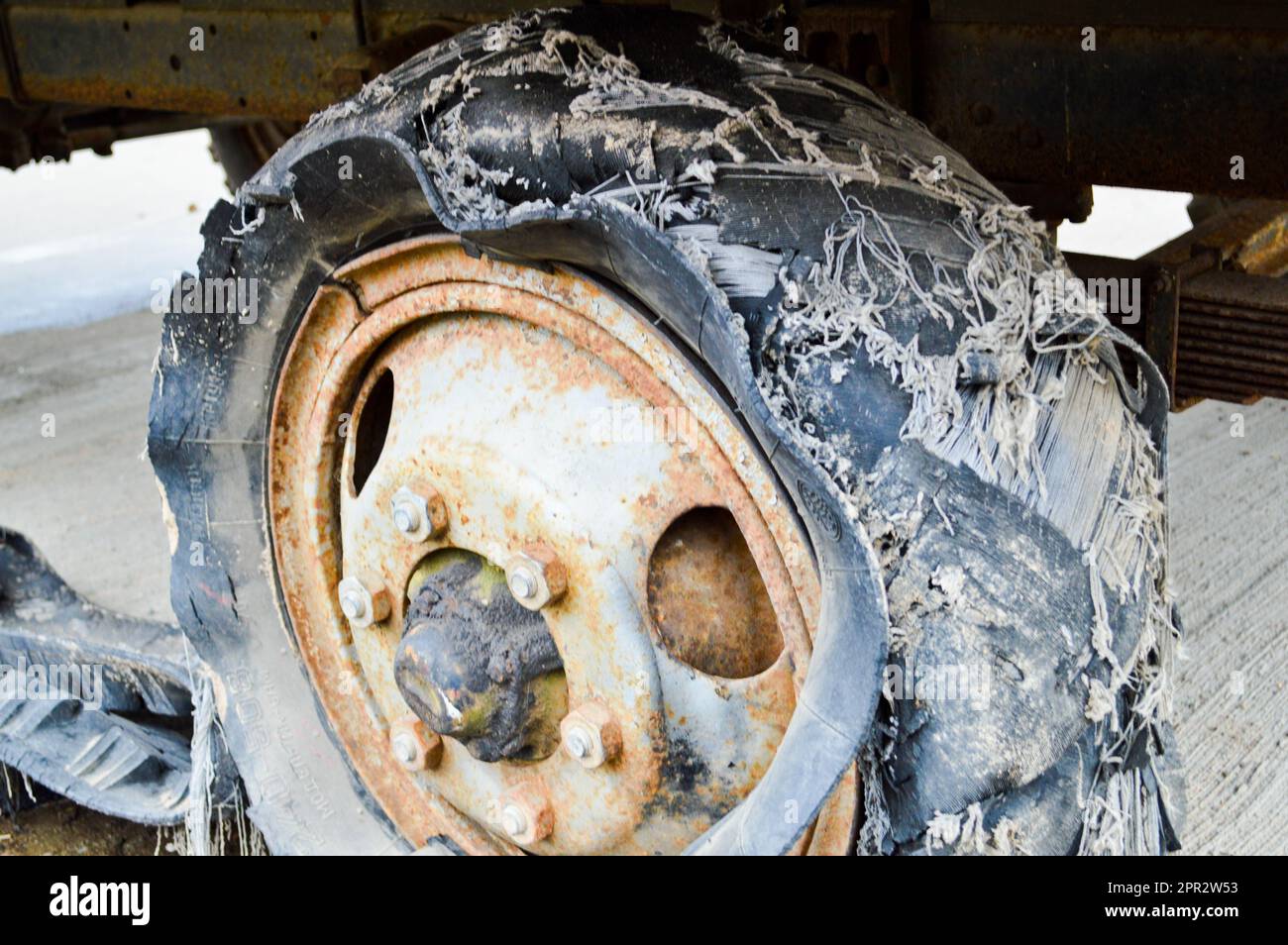 A large black rusty rubber wheel with a torn worn out broken bad old ...