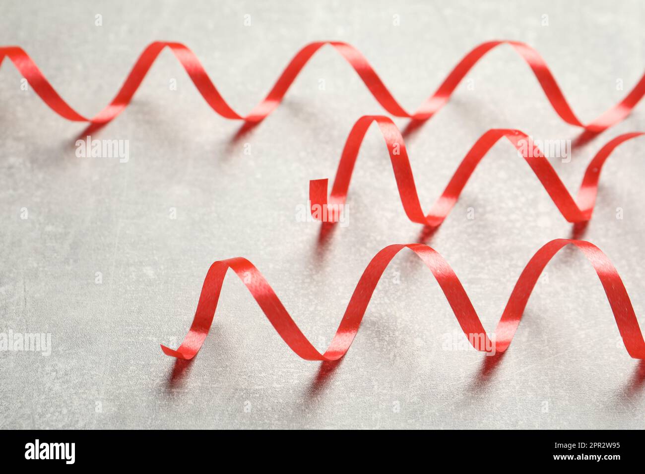 Shiny red serpentine streamers on grey background, closeup Stock Photo ...