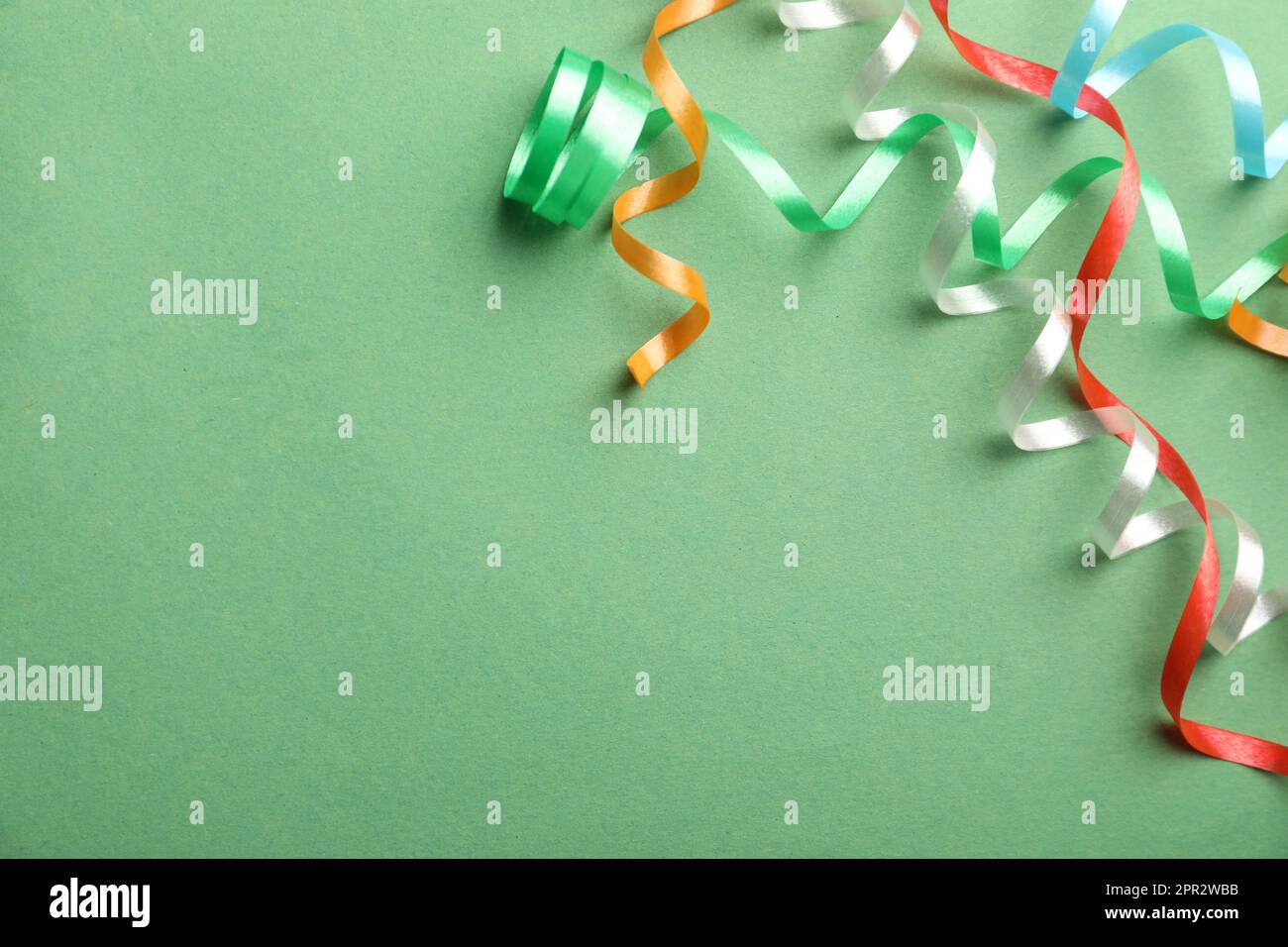 Colorful serpentine streamers on green background, flat lay. Space for ...
