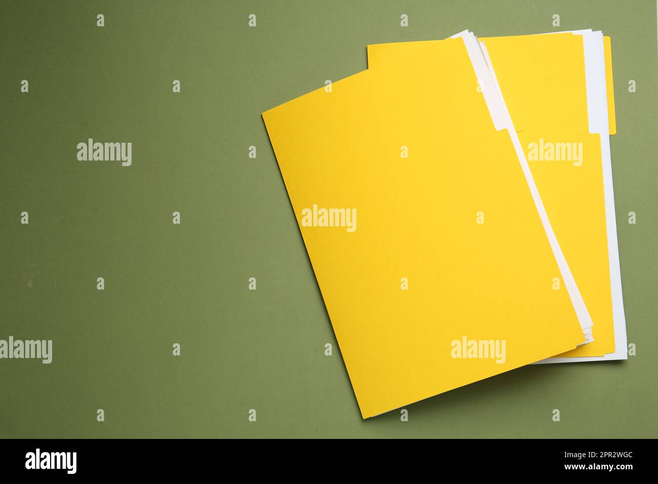 Yellow files with documents on olive background, top view. Space for ...