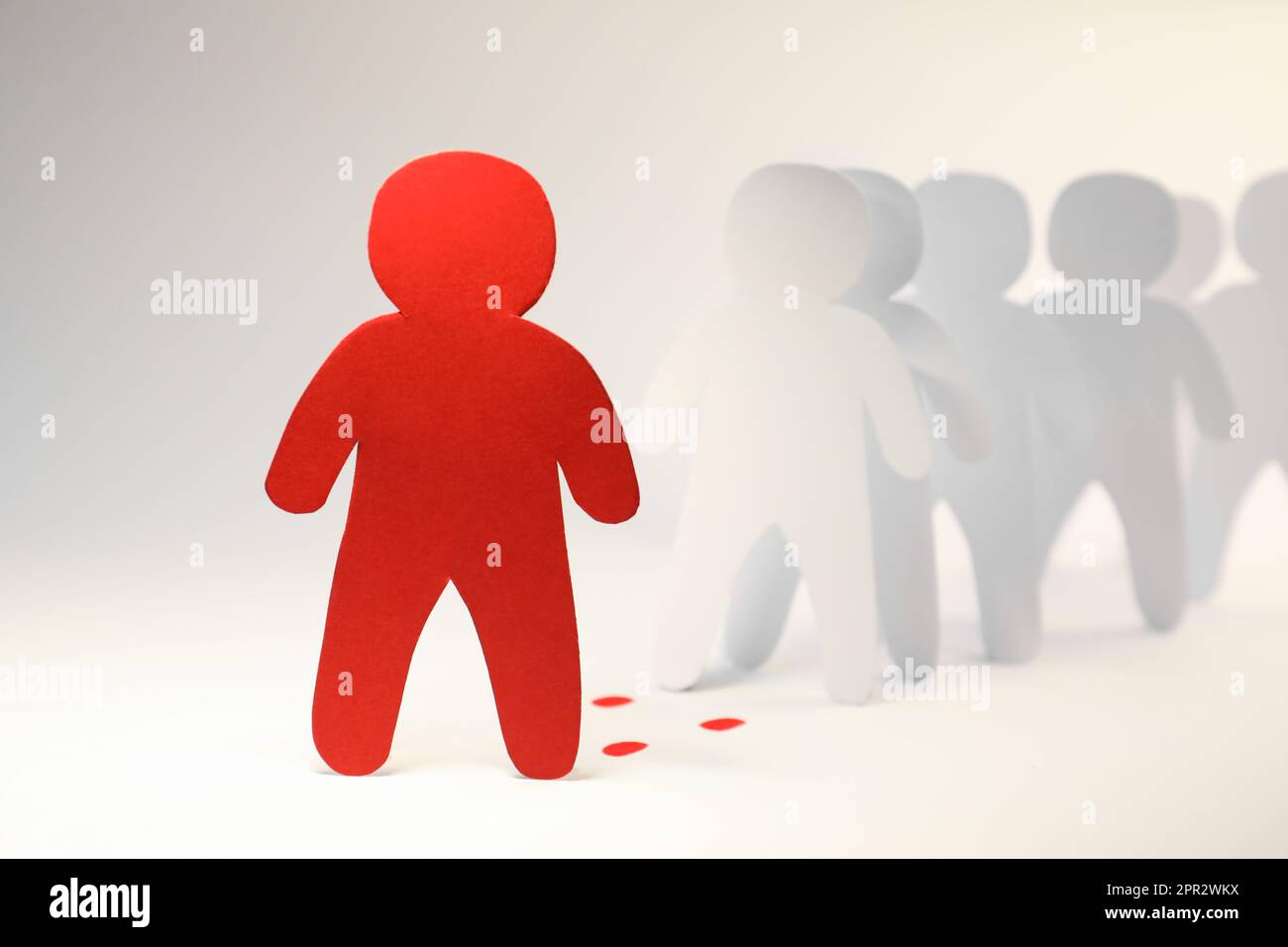 White paper human figures following red one on light background ...