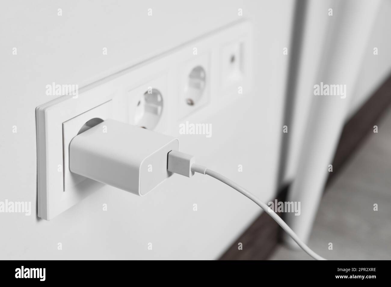 Charger adapter plugged in power socket indoors, closeup. Space for ...