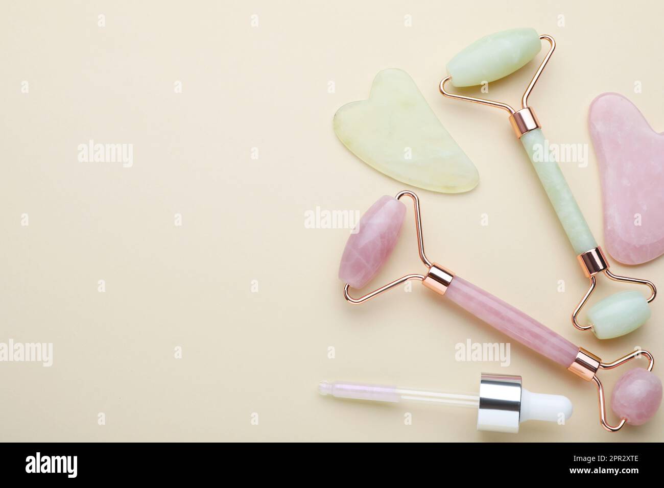 Gua sha tools, facial rollers and dropper on beige background, flat lay ...