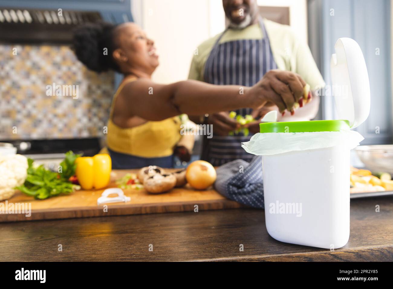 Happy senior african american couple wearing aprons and throwing waste ...