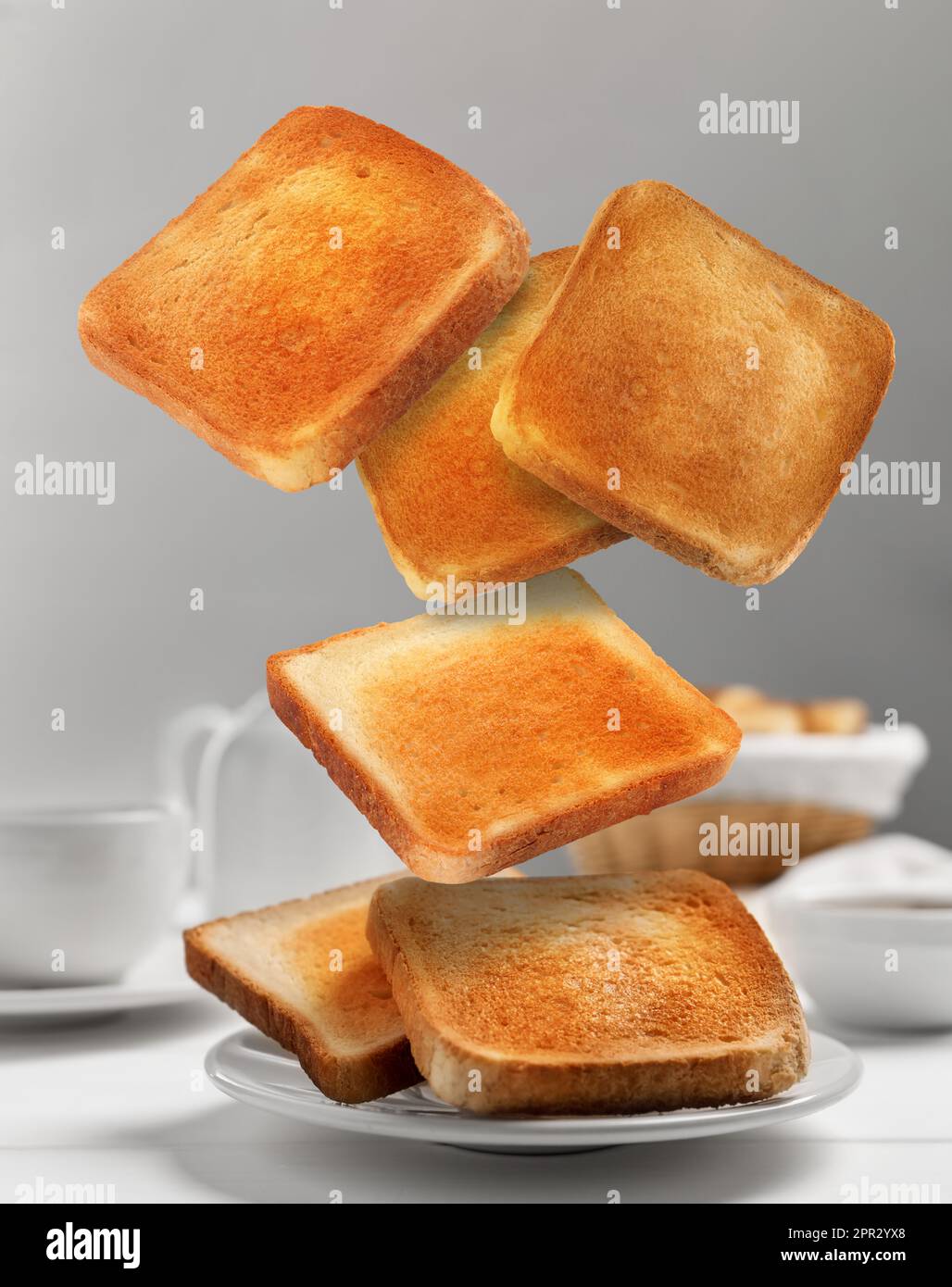 Delicious toasted bread falling into plate on white table Stock Photo ...
