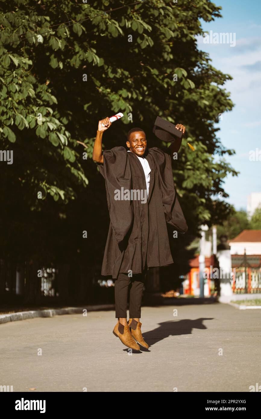 Rejoicing black guy graduate from university bouncing with happiness in ...