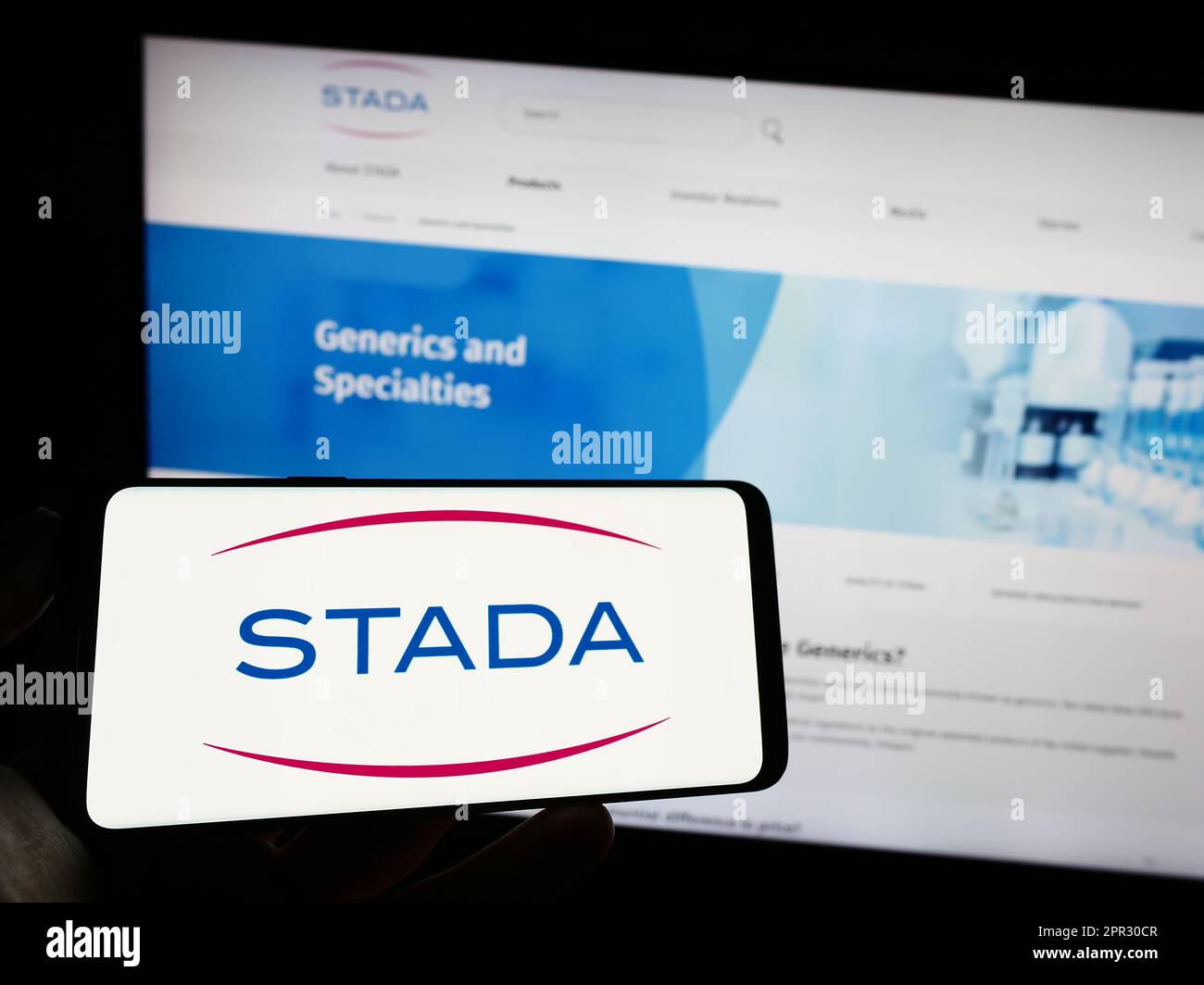 Person holding mobile phone with logo of German company Stada ...
