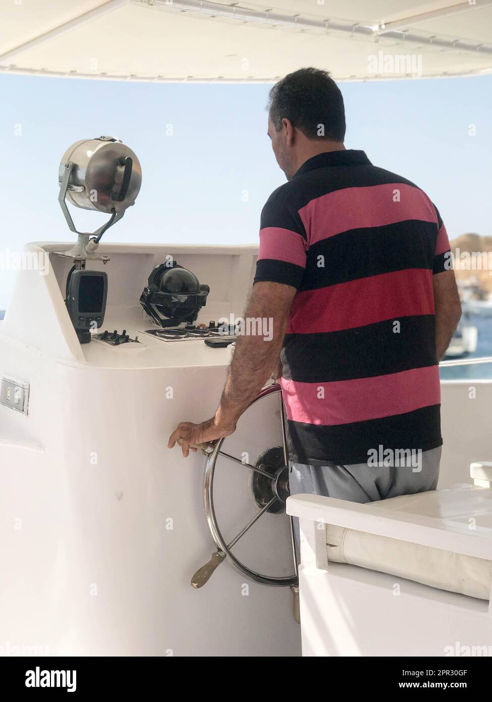 The swarthy captain of the man in the red striped T-shirt manages the ...