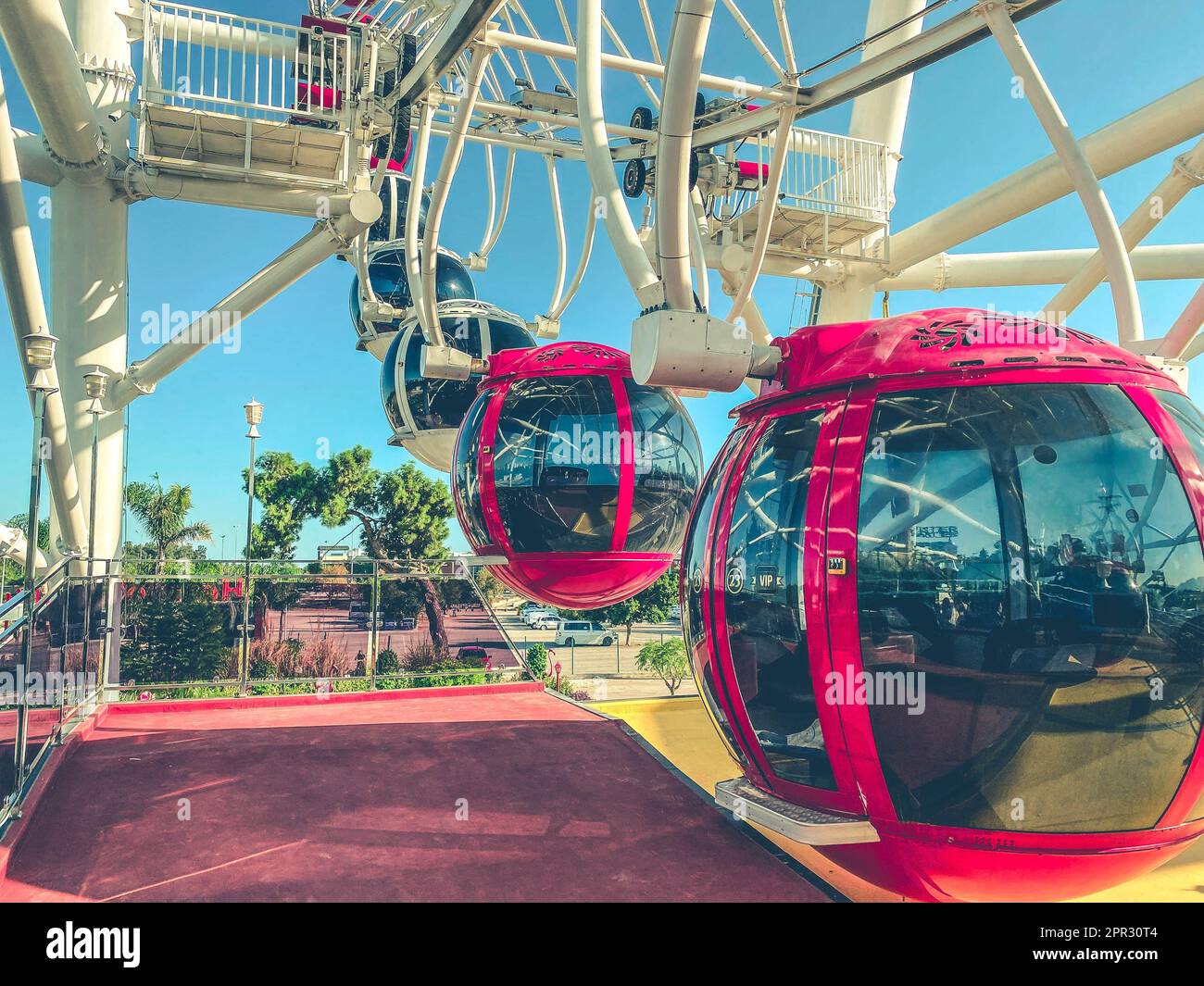 Ferris wheel in the city center against the blue sky. red cabins with ...