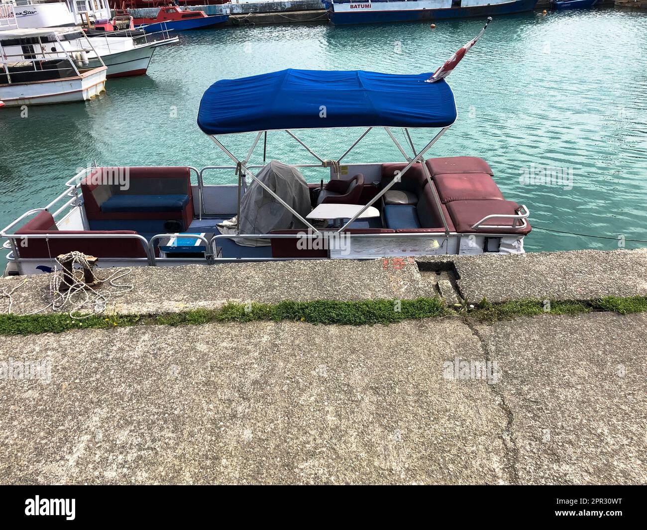 A small boat with a stretch canvas roof stands on the quay at the port ...
