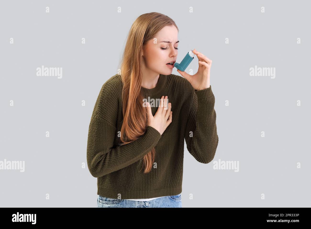 Young woman with inhaler on grey background Stock Photo - Alamy