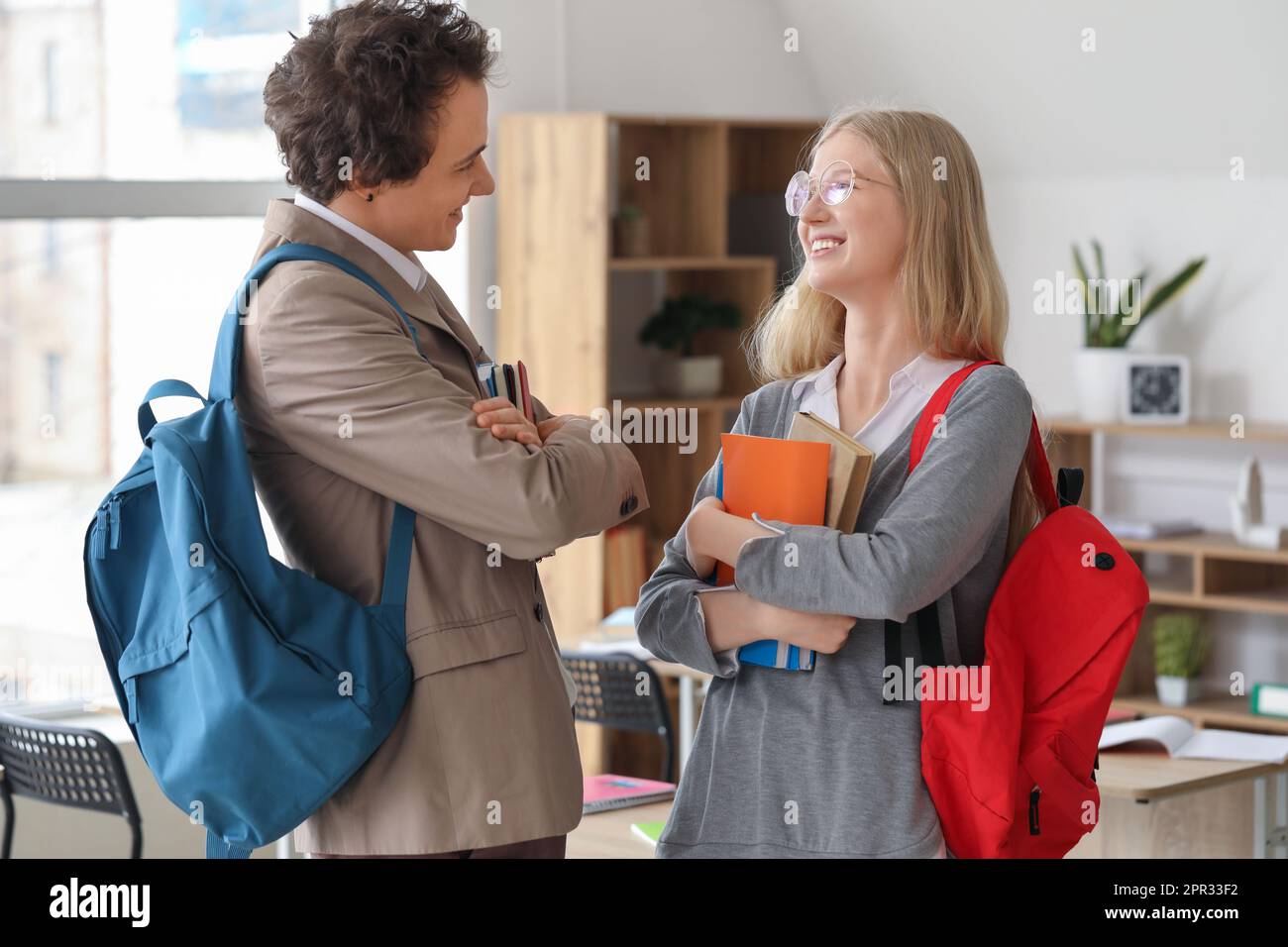 Cute teenage couple with books in classroom Stock Photo - Alamy